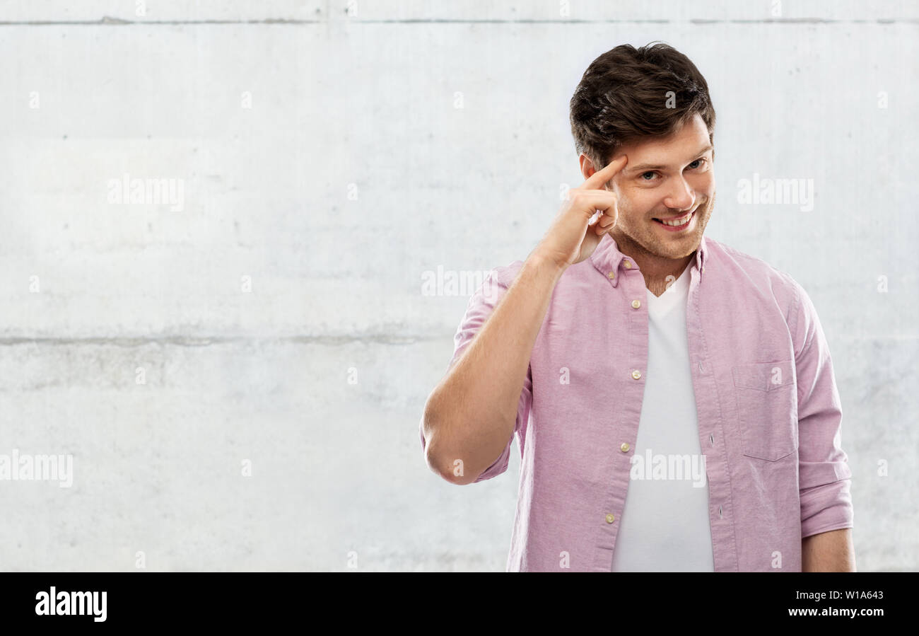 smiling young man pointing finger to his head Stock Photo - Alamy