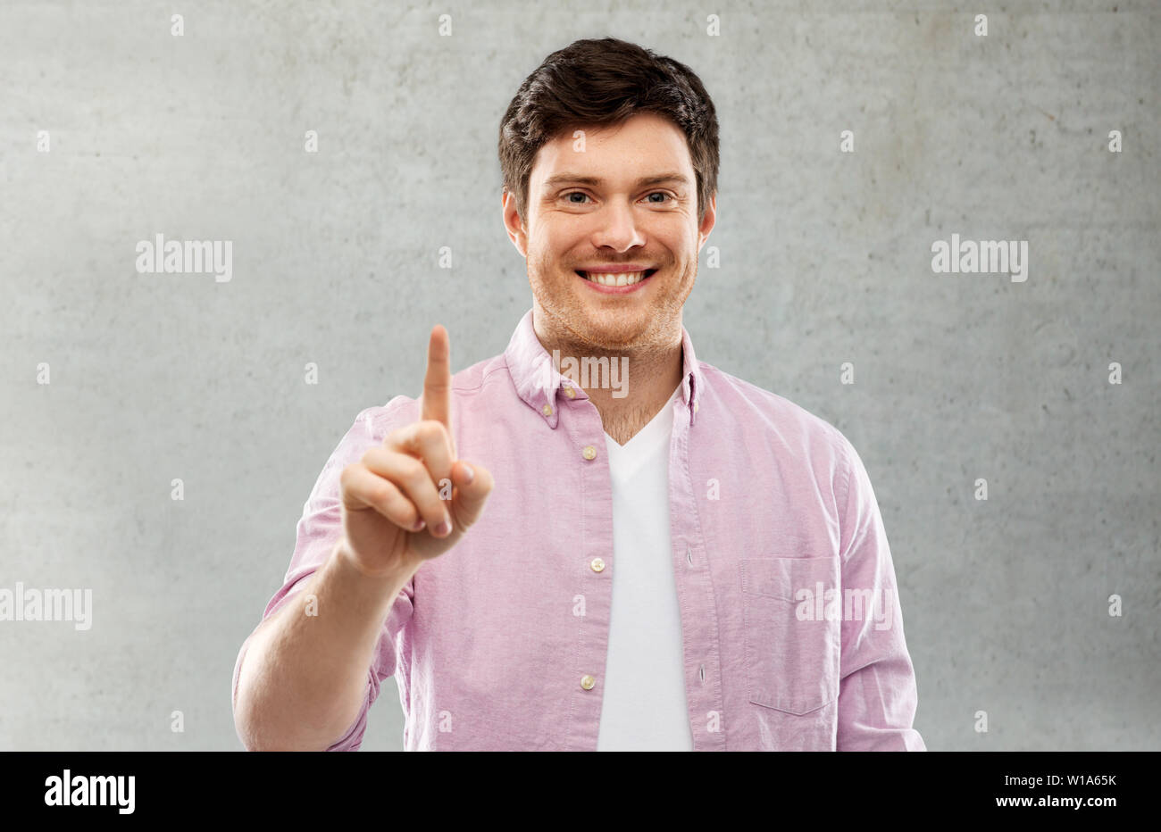 man showing one finger over gray concrete wall Stock Photo - Alamy