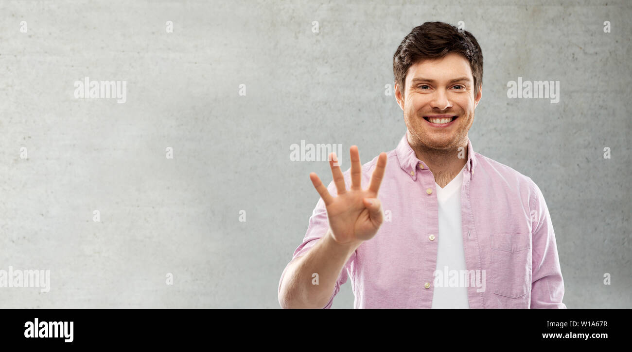 man showing four fingers over grey concrete wall Stock Photo - Alamy
