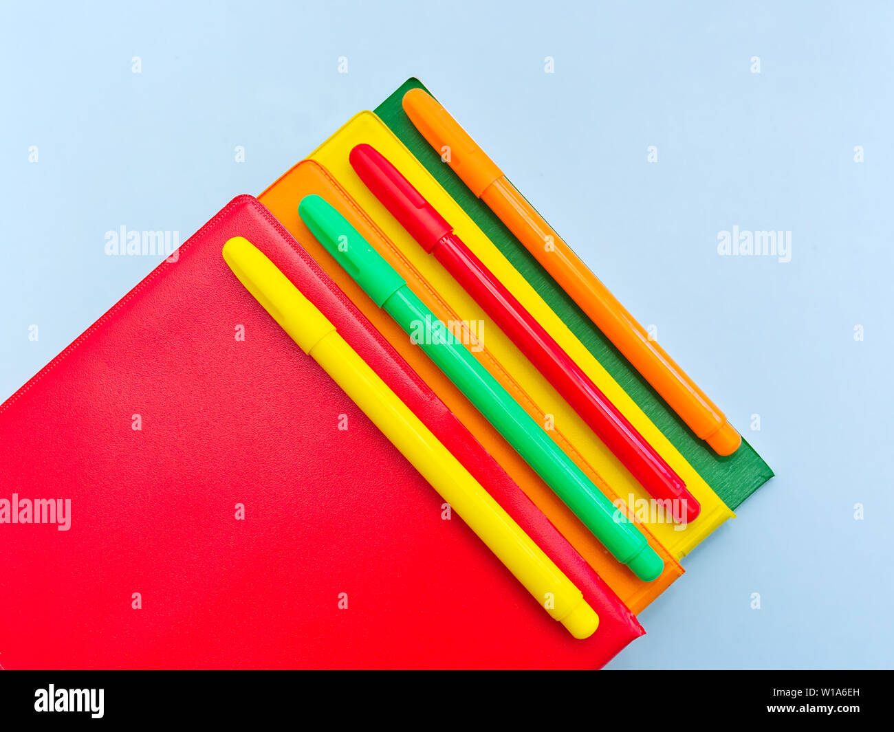 Colorful school supplies notebooks and markers on light blue background ...