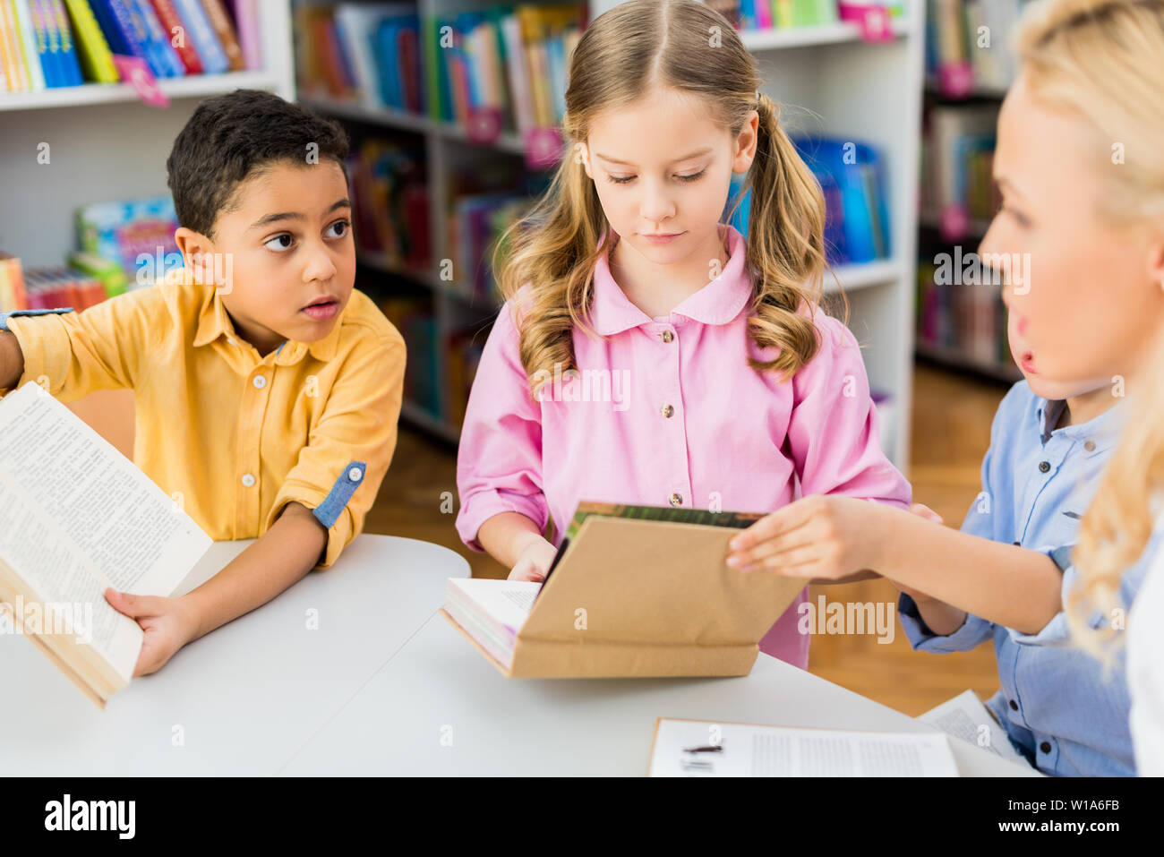 selective focus of cute kid reading book near african american child ...