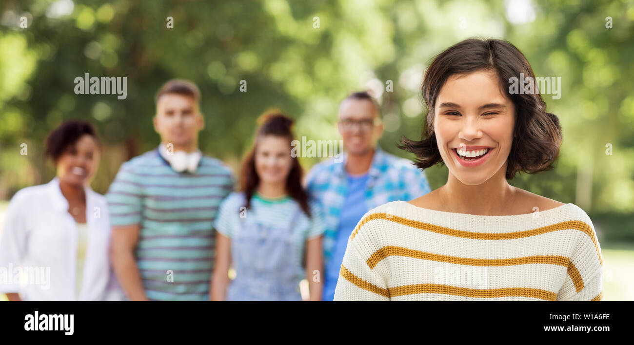 happy woman winking at summer park with friends Stock Photo - Alamy