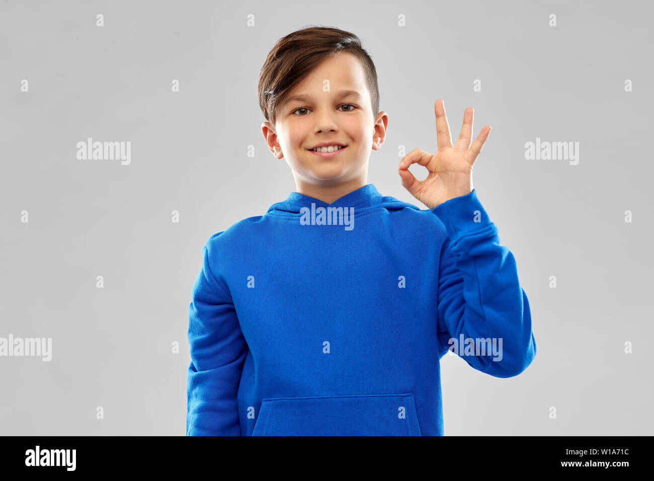 boy in blue hoodie showing ok hand sign Stock Photo - Alamy