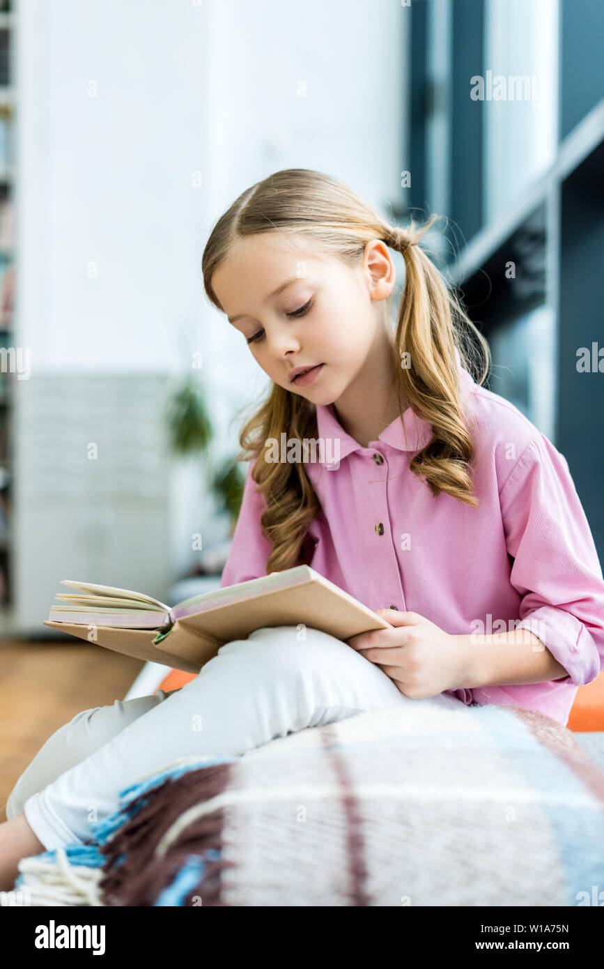 selective focus of cute kid sitting and reading book Stock Photo - Alamy