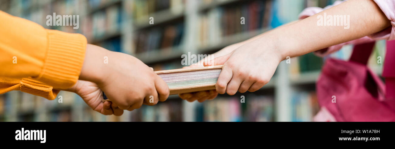panoramic shot of kids pulling book while standing in library Stock ...