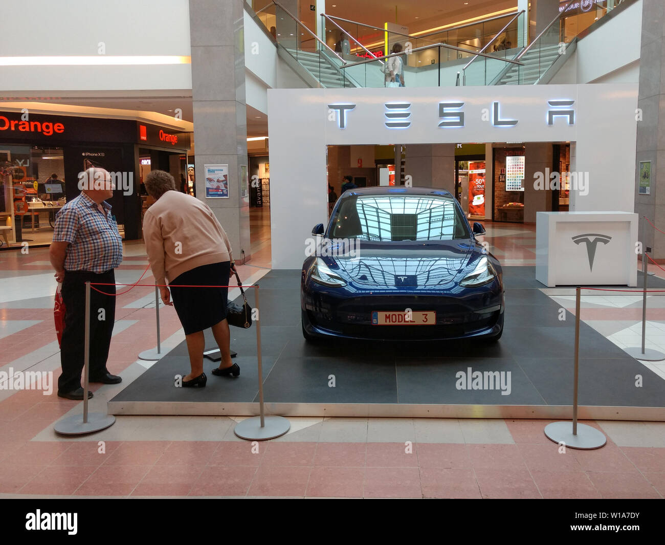 Elderly couple inspecting a Tesla Model 3 on display in a mall Stock ...