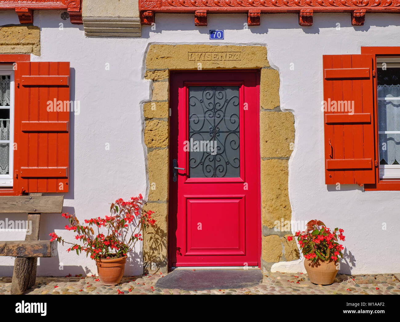 Red door facade of typical French basque house, with potted plants ...