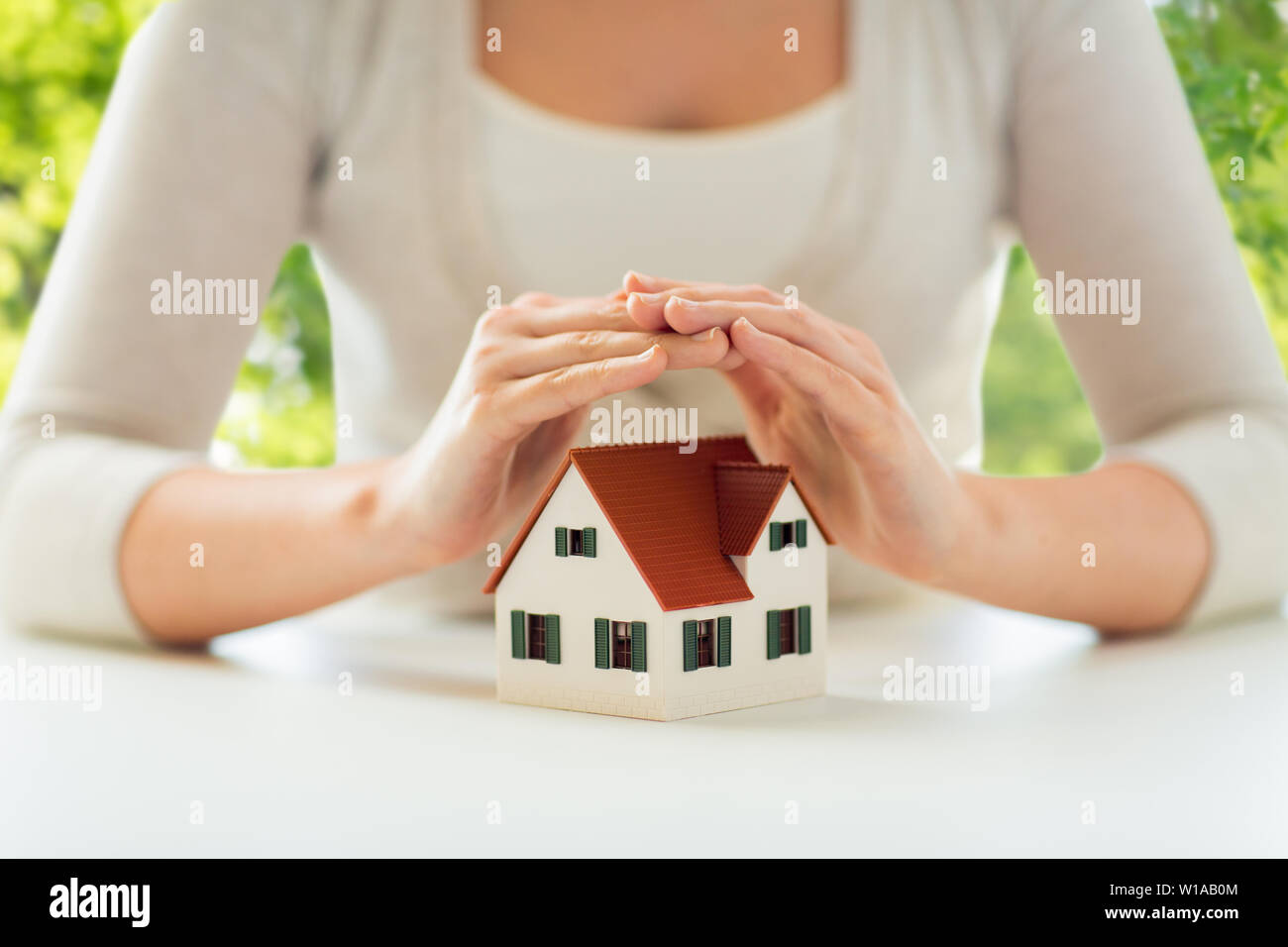 close up of woman protecting house model by hands Stock Photo - Alamy