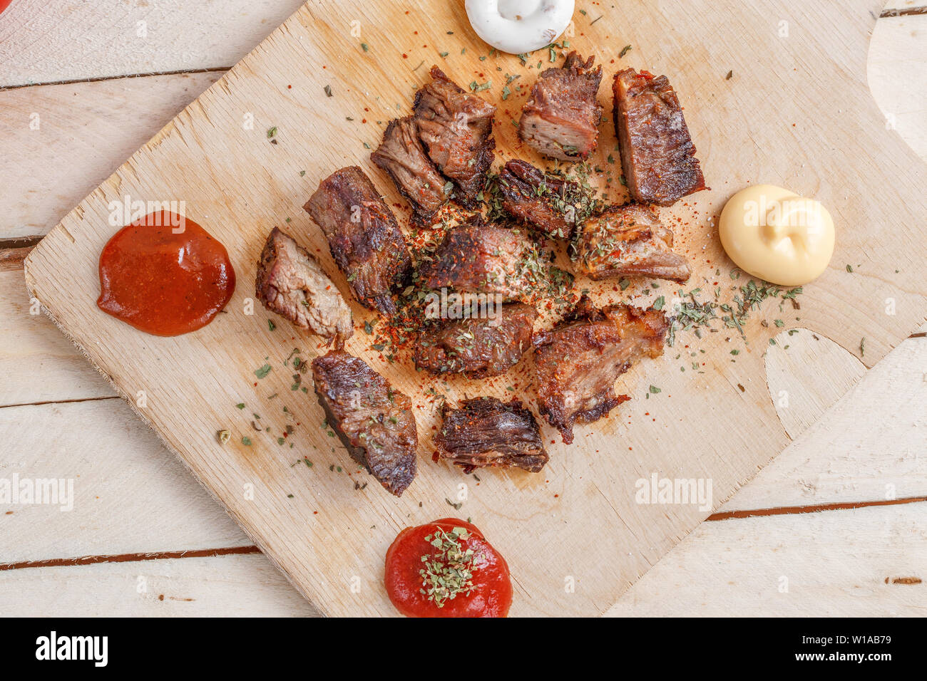 pieces of roasted meat with spices on a wooden tray with four kinds of ...