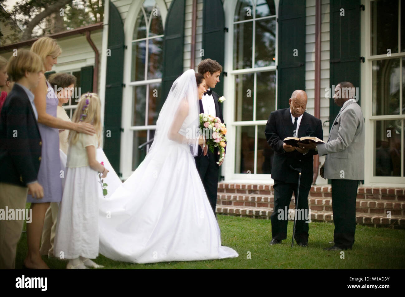 Senior adult man performing a wedding ceremony for a young adult bride ...