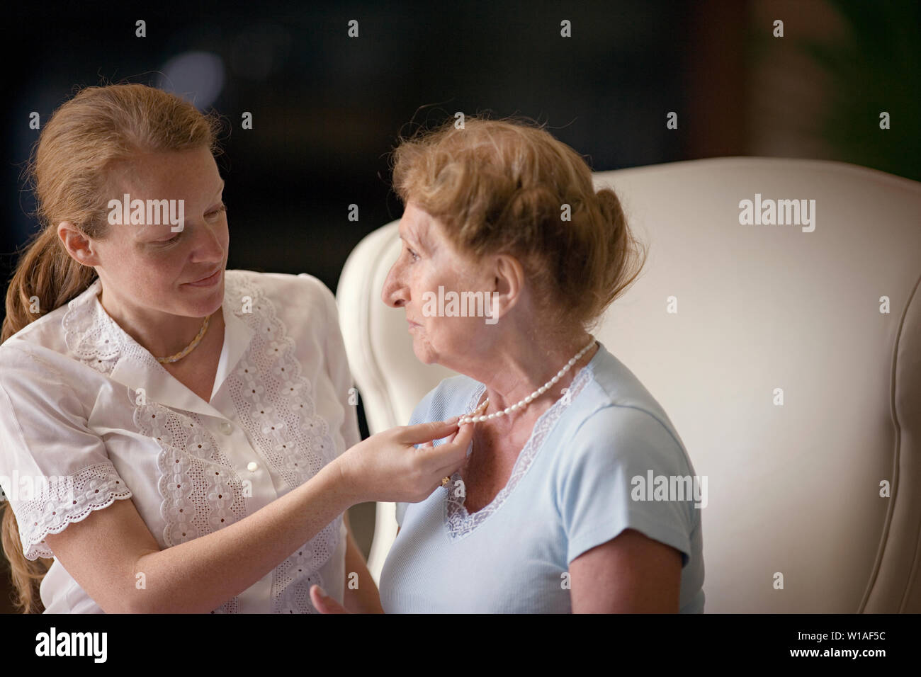 Portrait of a woman inspecting the pearl necklace of an elderly lady ...
