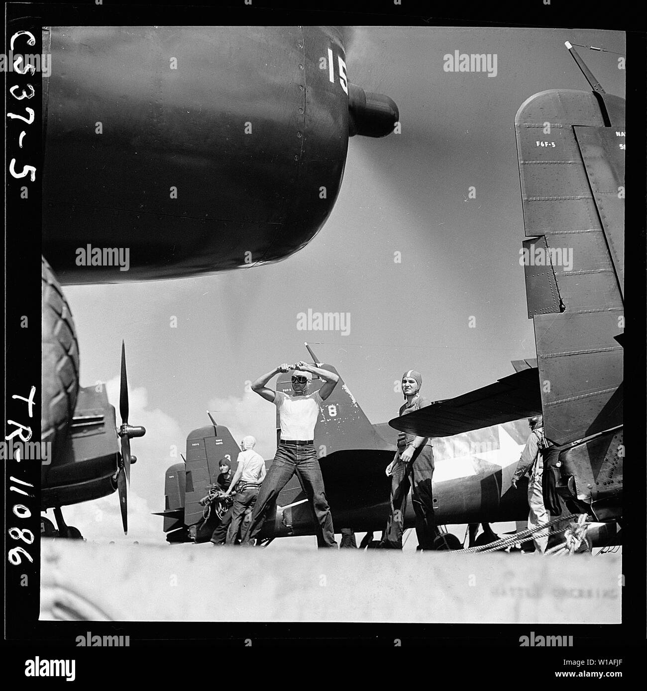 A plane handler giving the signal, Lock tailwheel, to an F6F pilot ...