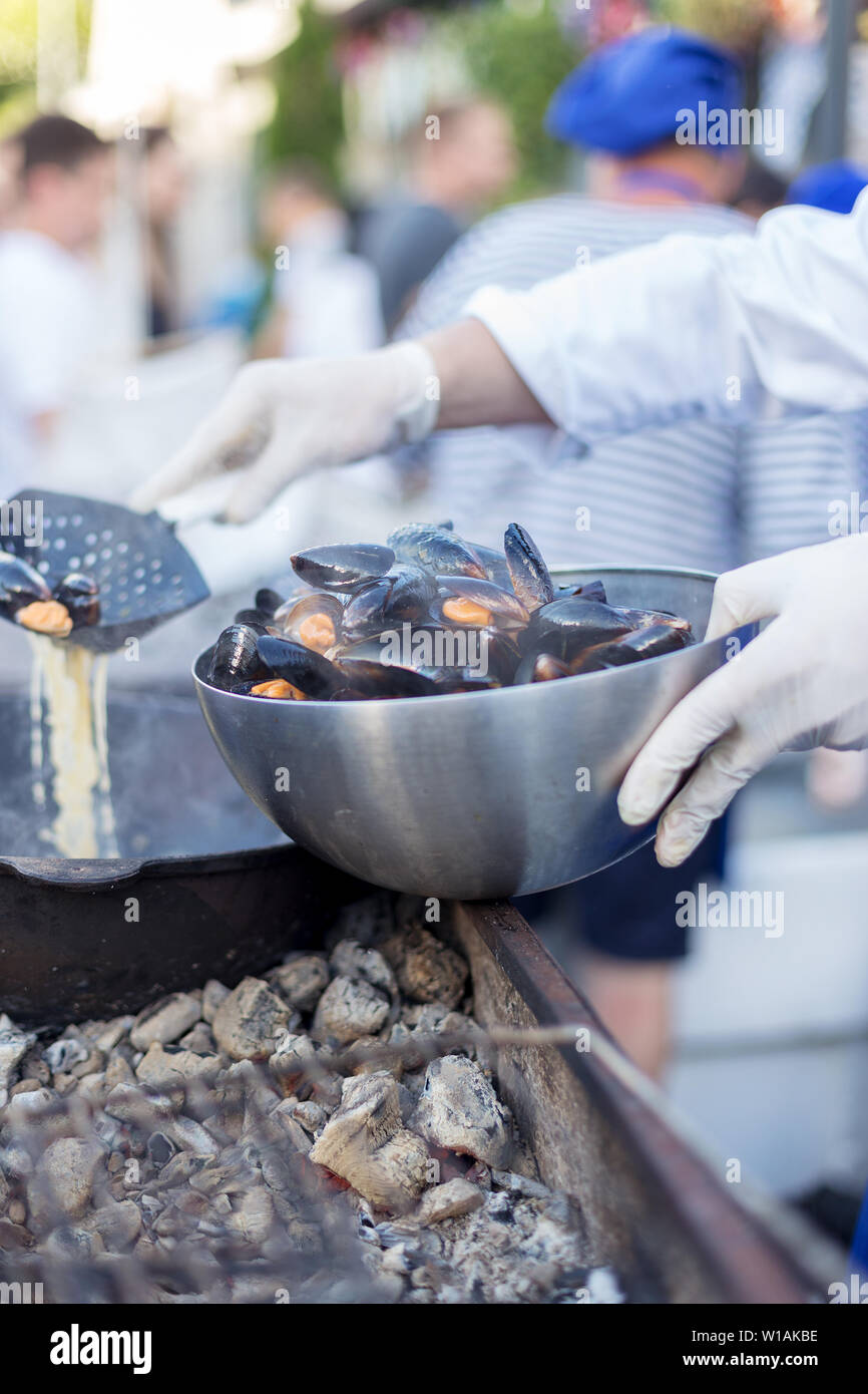 Men's hand cook fresh mussels on open fire. Concept of street food ...