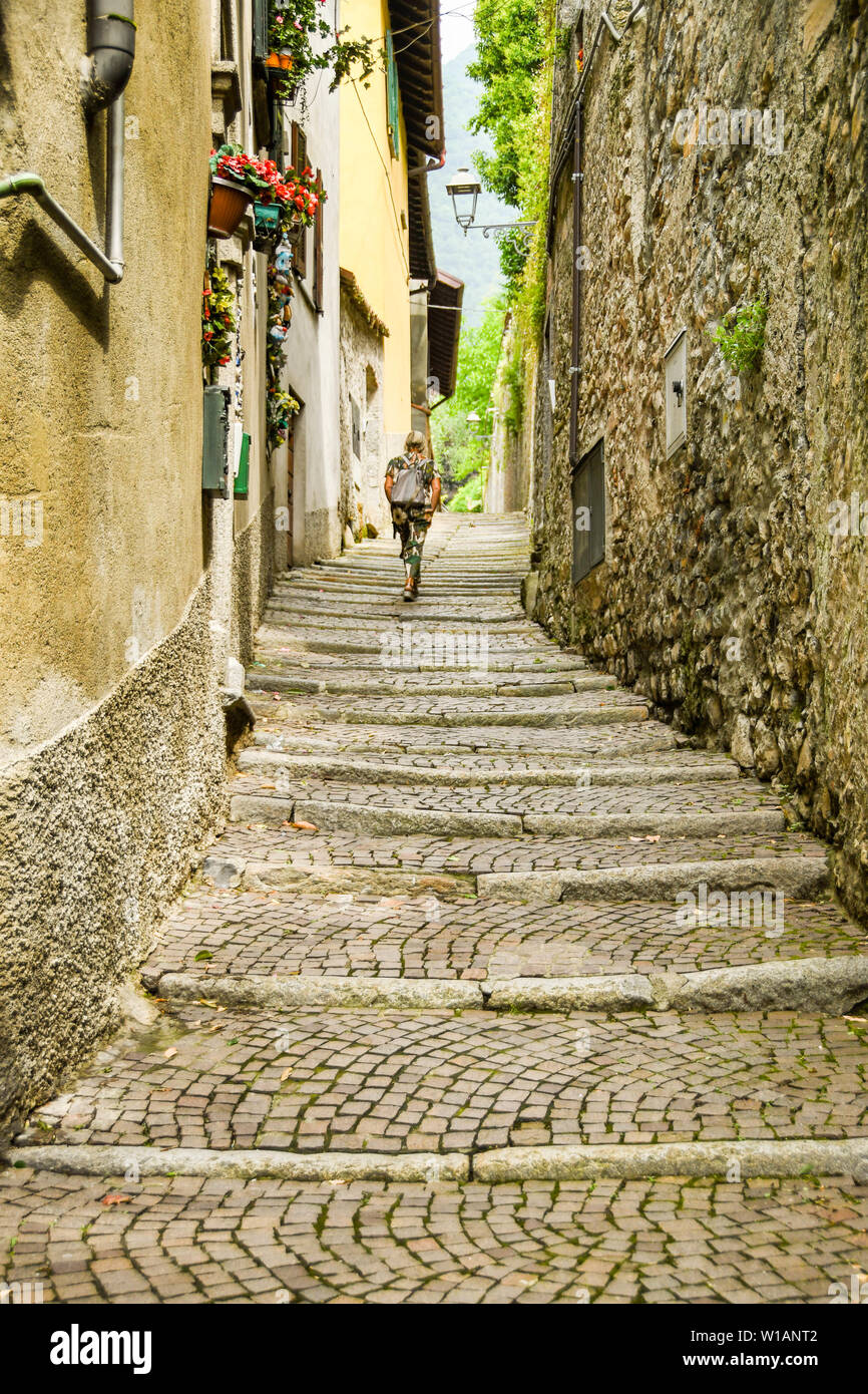 LAKE COMO, ITALY - JUNE 2019: Person walking up a narrrow lane with ...