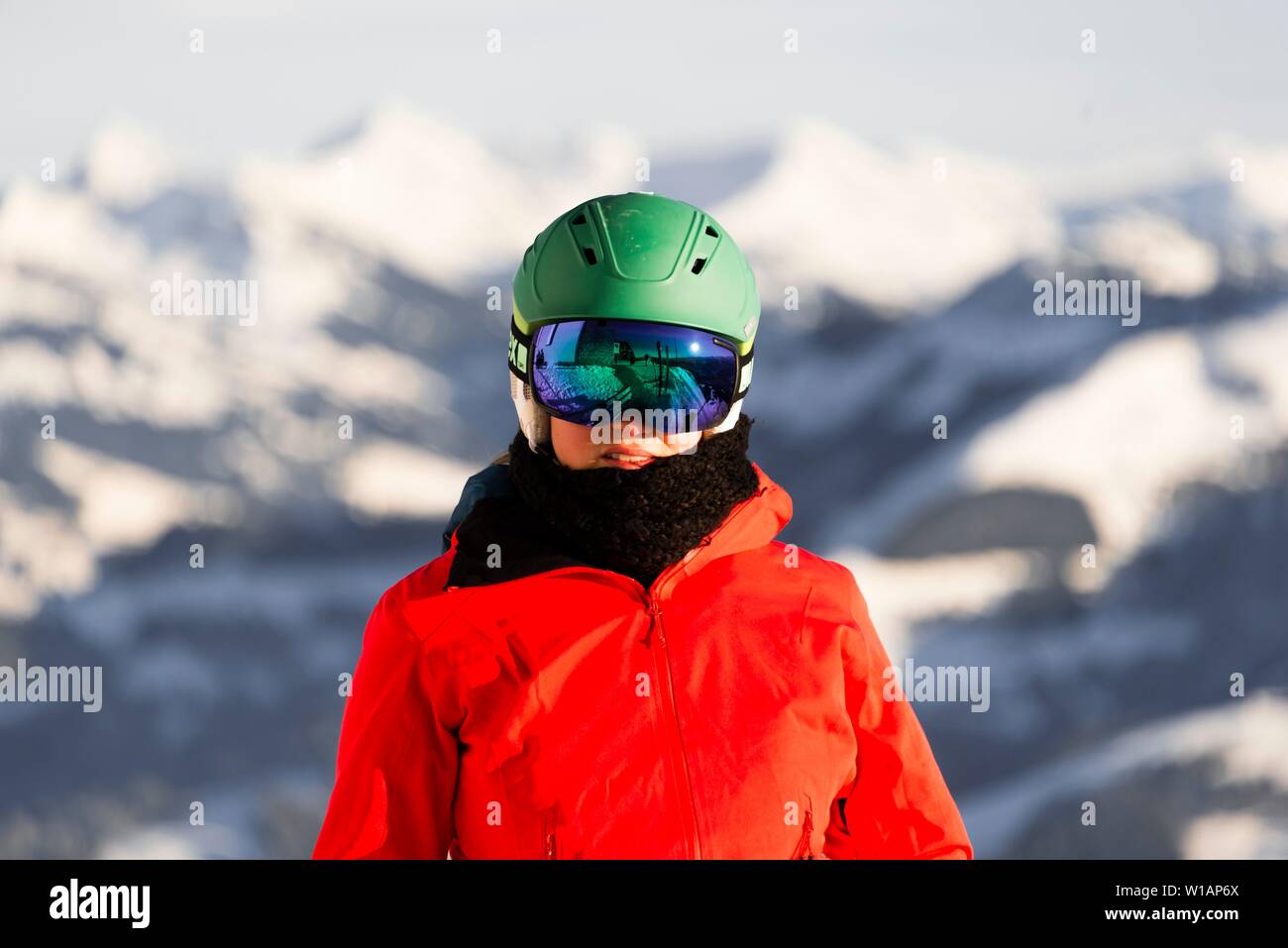 Female skier with ski helmet and ski goggles looks into the camera ...