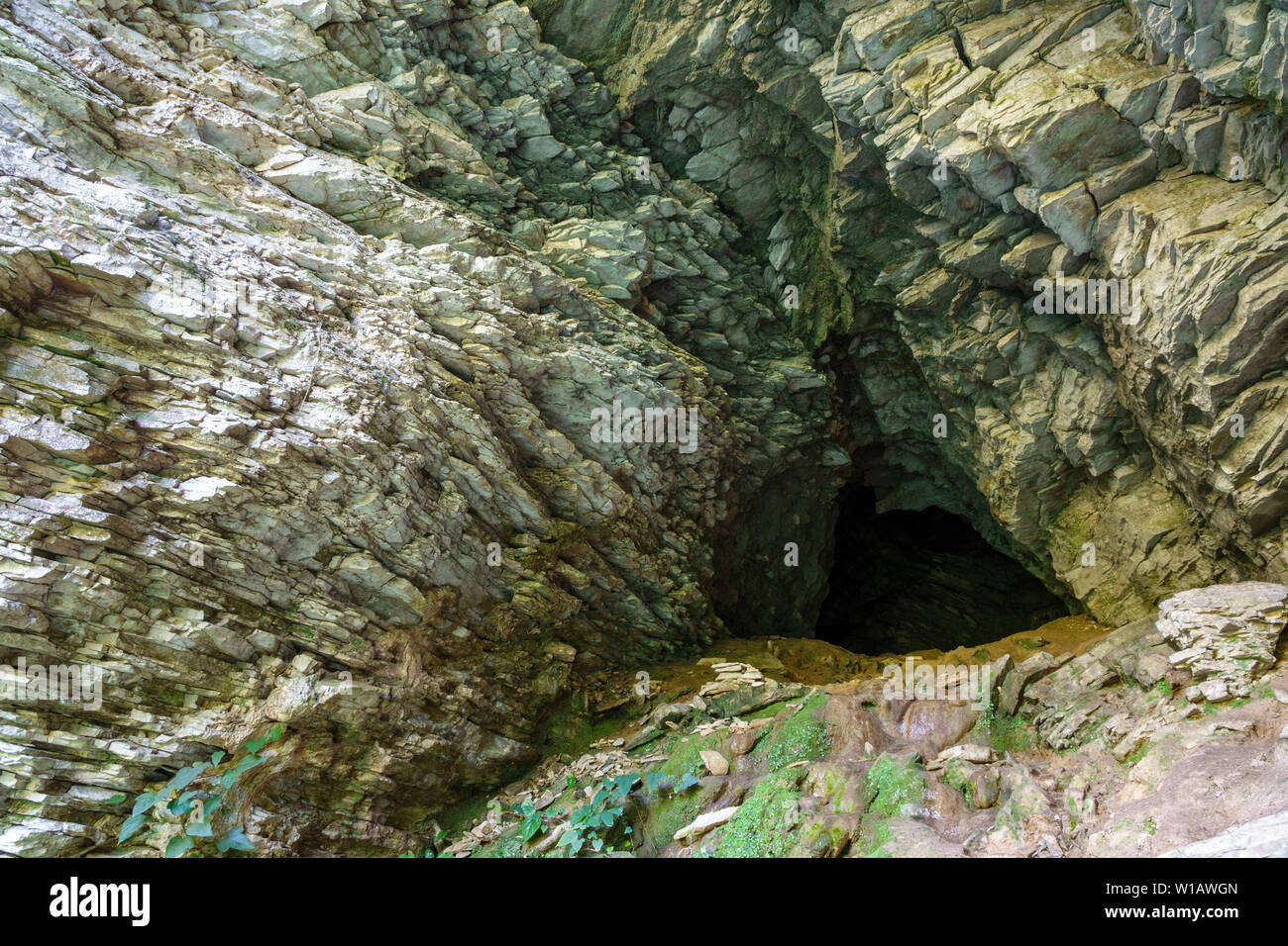 Limestone cliff wall with entrance of the cave. Cave in a layered ...
