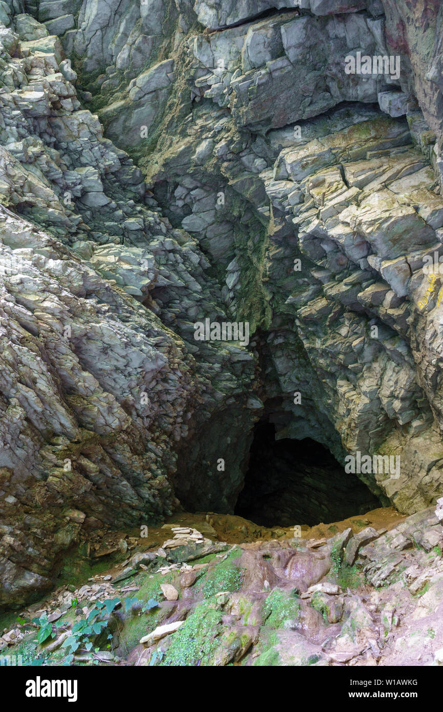 Limestone cliff wall with entrance of the cave. Cave in a layered ...