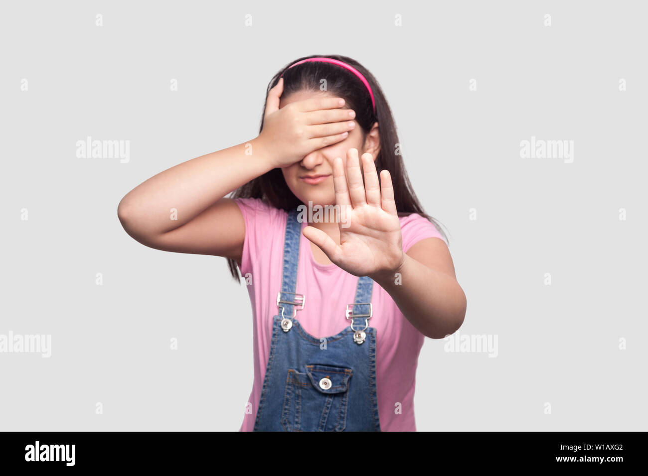 I don't want to look at this. Portrait of scared or shy girl in pink t ...