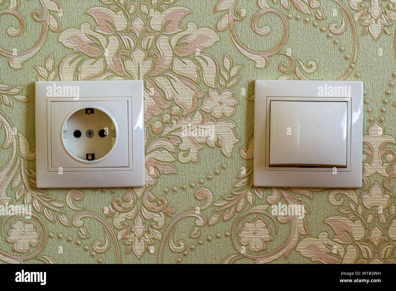 Electrical switch and plug on wall with wallpapers Stock Photo - Alamy