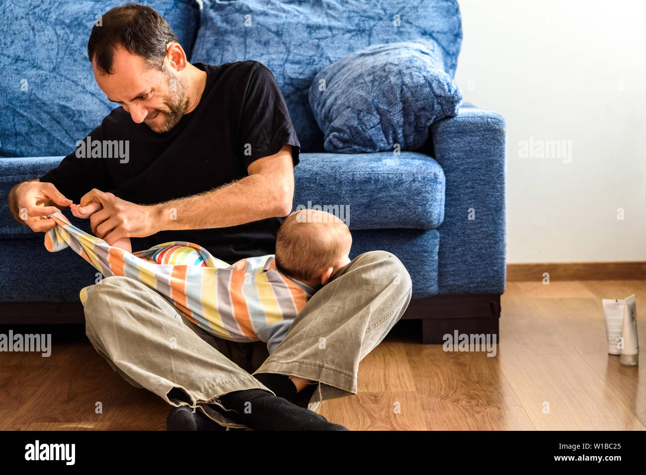 Novice father changing clothes to his baby with effort in the living ...
