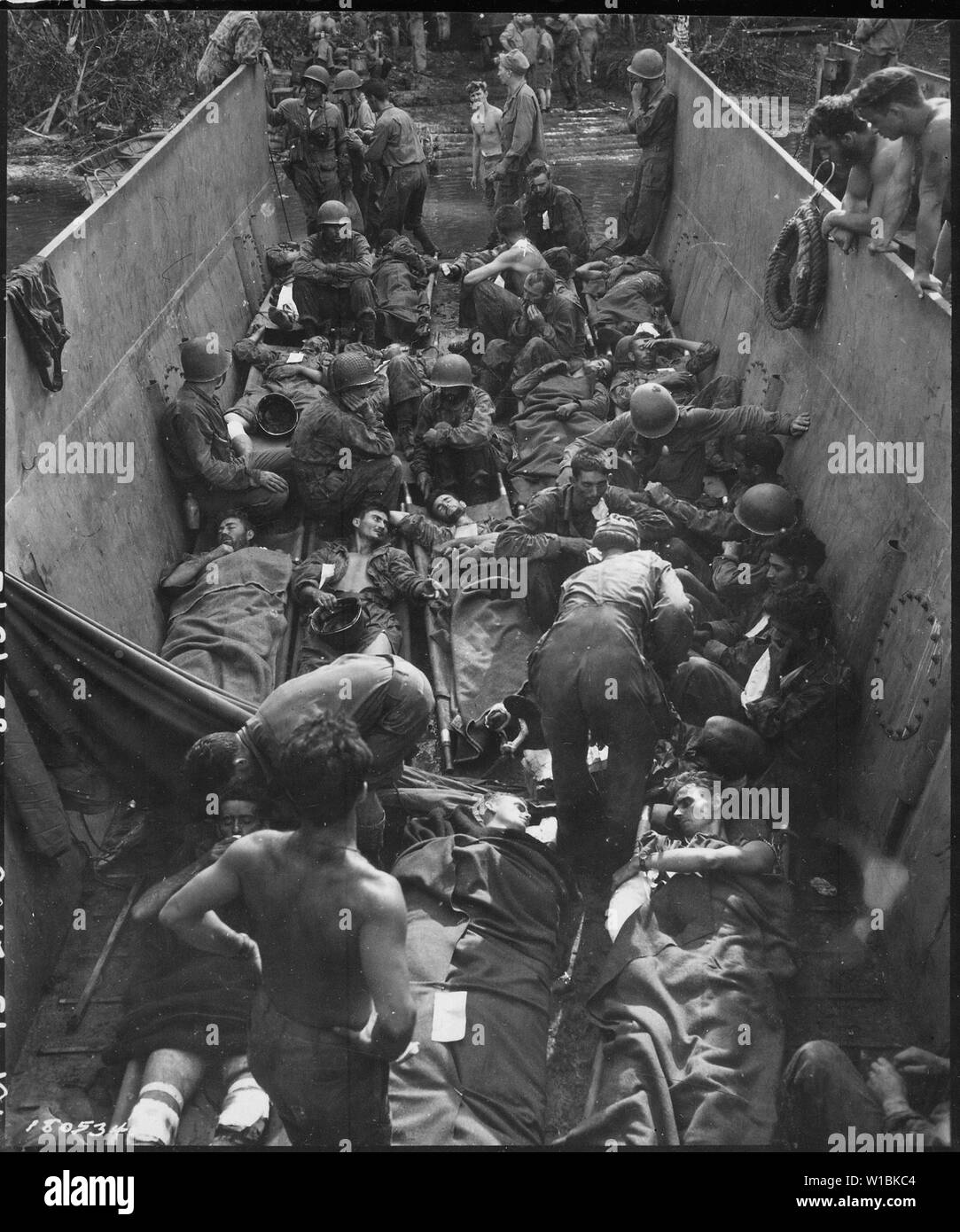 Casualties shown lying on stretchers aboard lighter, Munda Point, New ...
