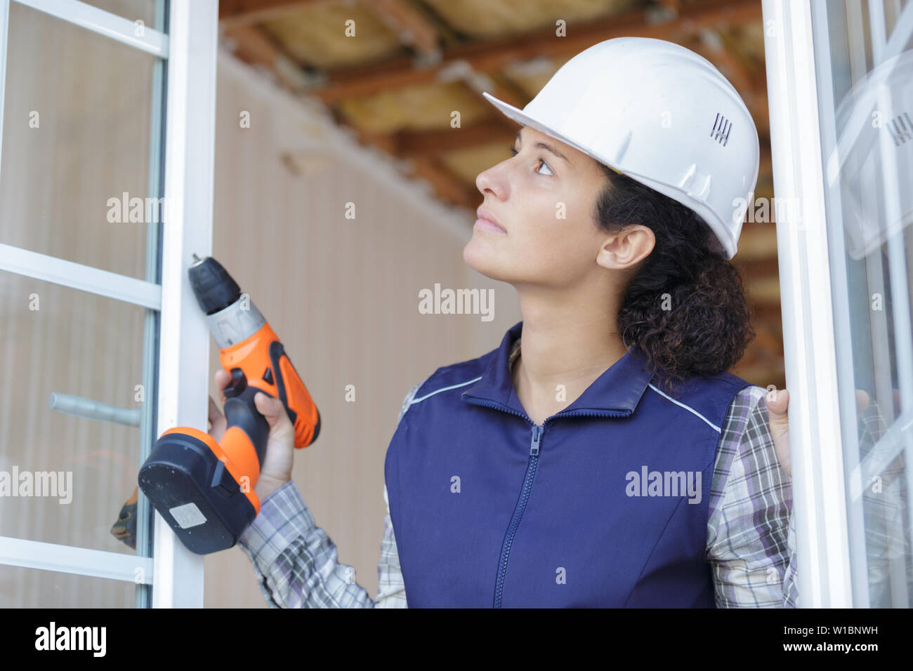 female window fitter holding cordless drill Stock Photo - Alamy