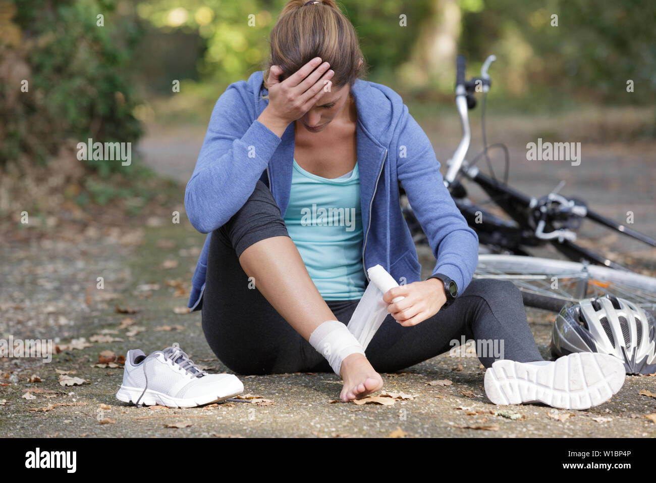 woman bandaging knee after falling from bicycle Stock Photo - Alamy