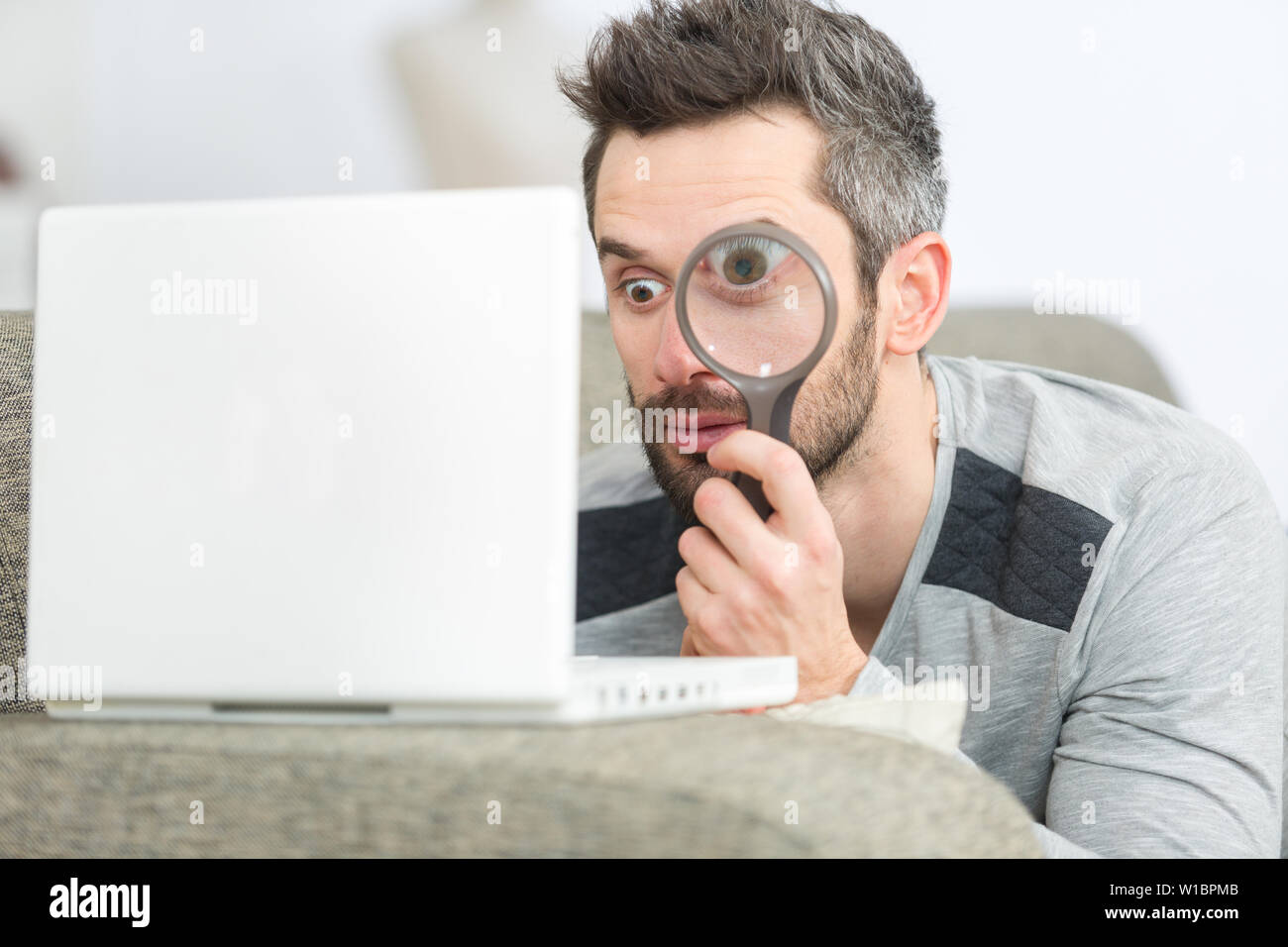 man using a magnifying glass on the laptop Stock Photo - Alamy