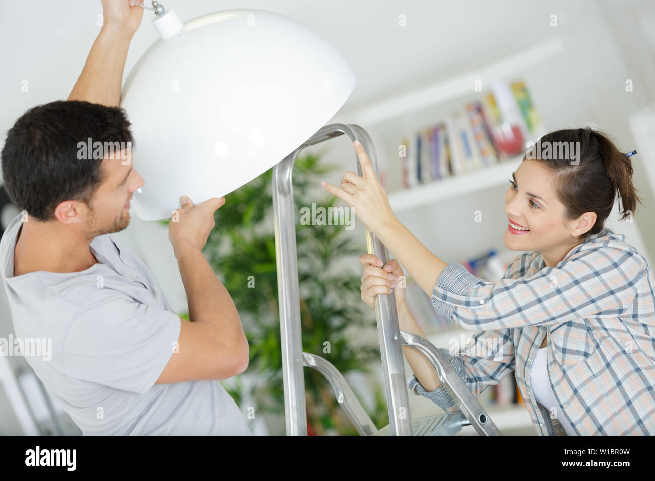couple installing the lamp on the ceiling Stock Photo - Alamy