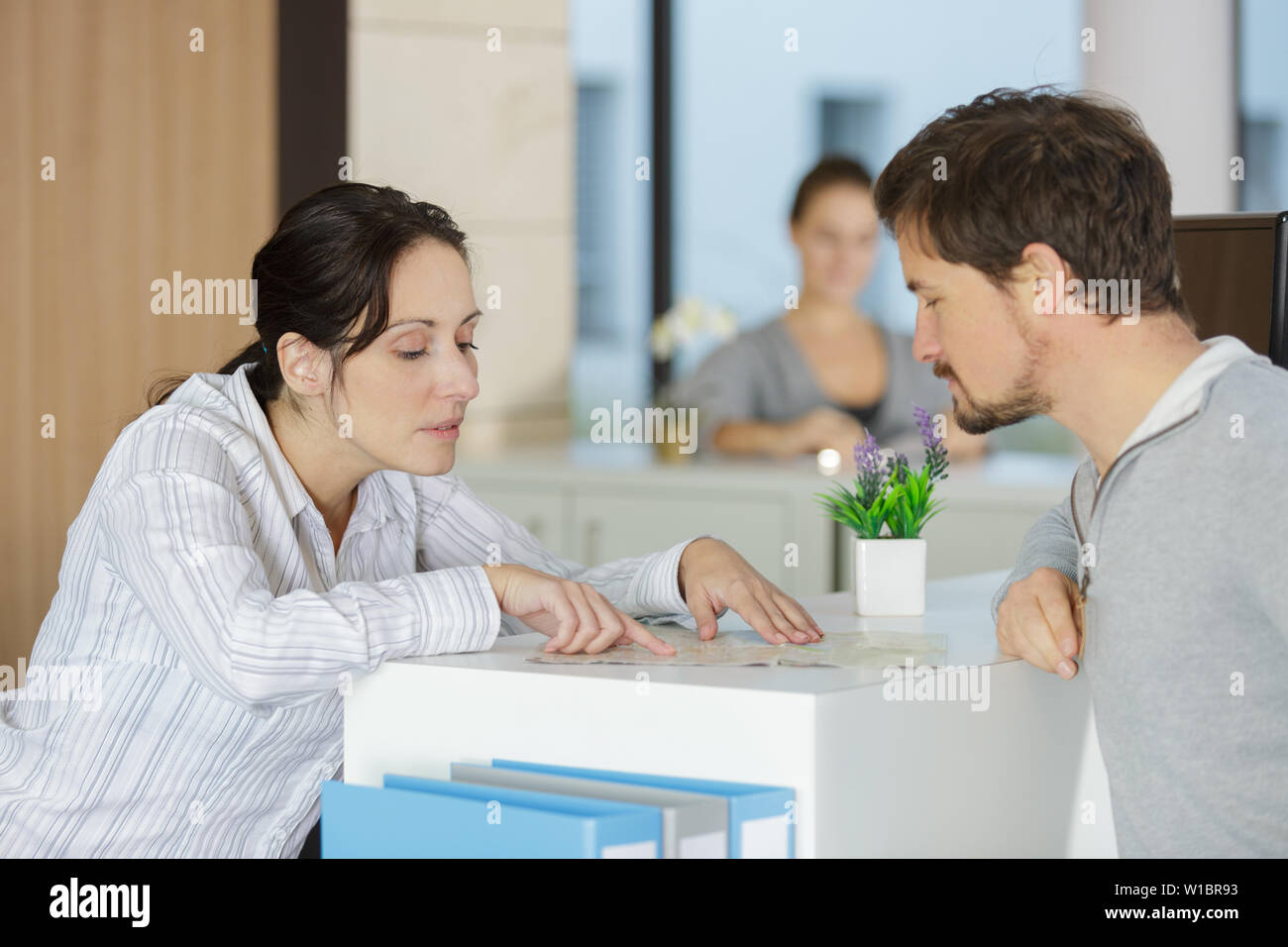 secretary welcoming client at office reception desk Stock Photo - Alamy