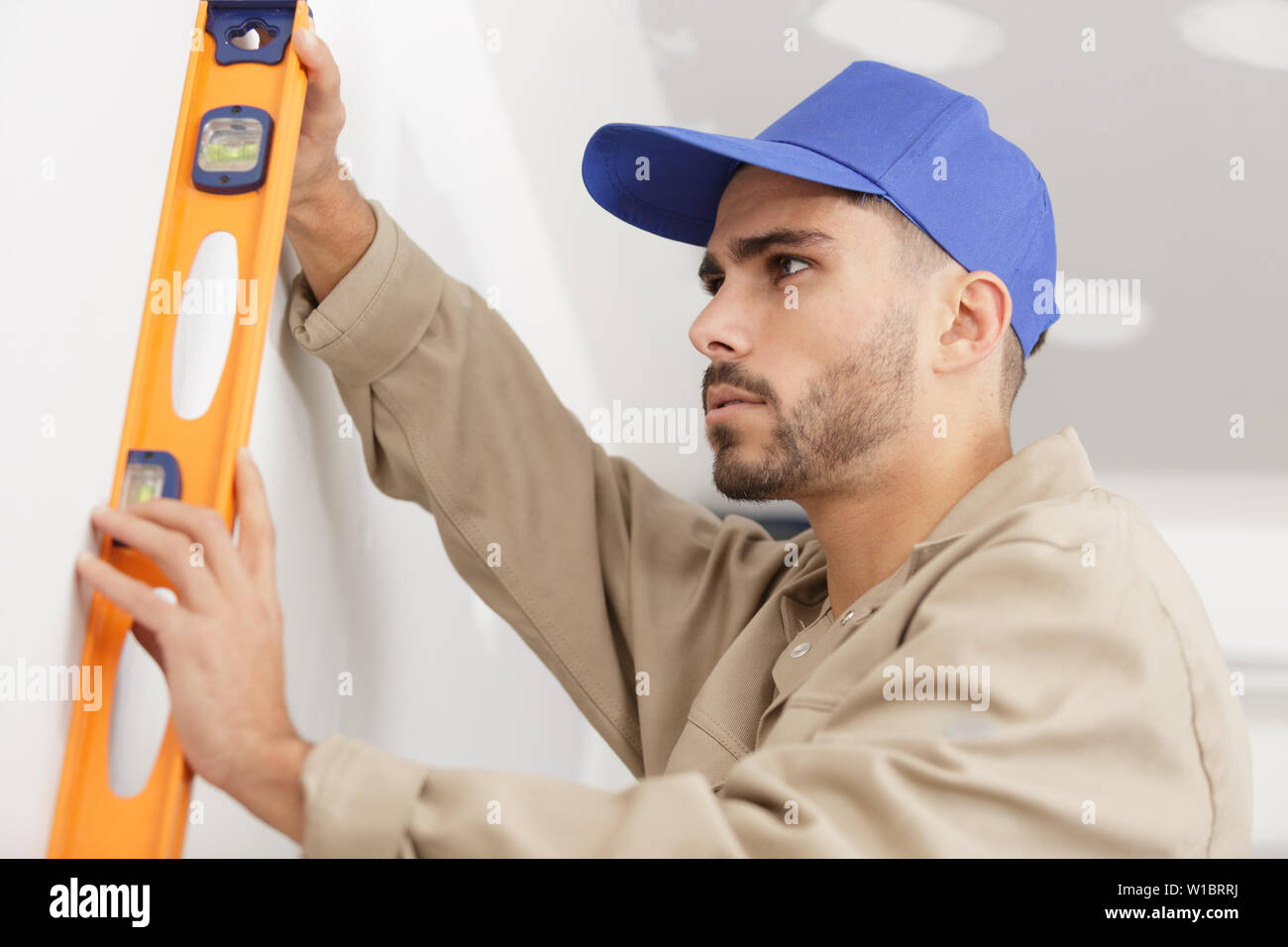 young man measuring wall with level Stock Photo - Alamy