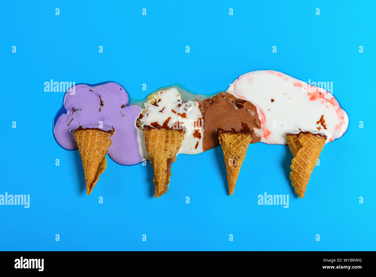 top view multiple flavor ice cream cones melted on blue background ...
