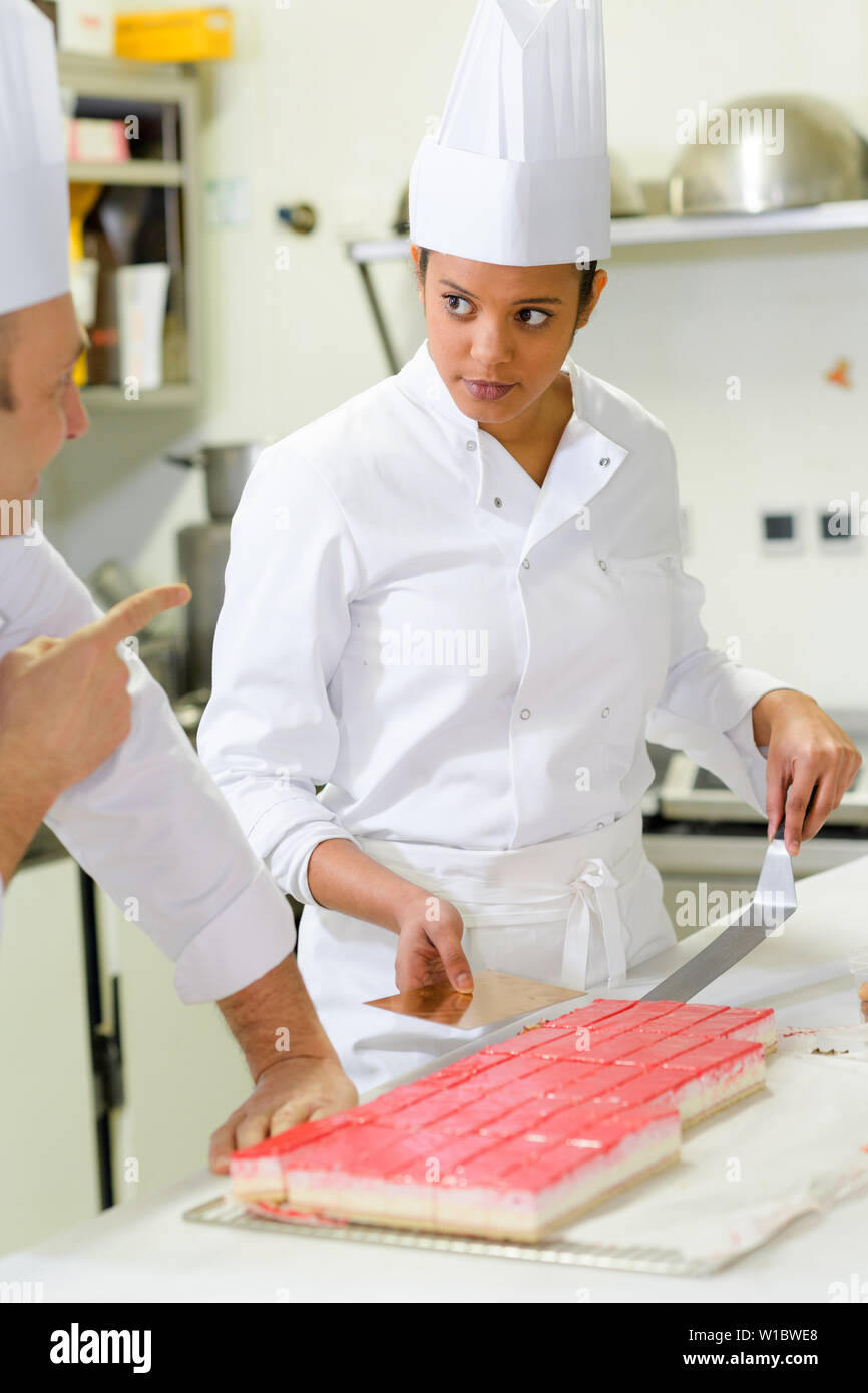female confectionery apprentice slicing a cake Stock Photo - Alamy