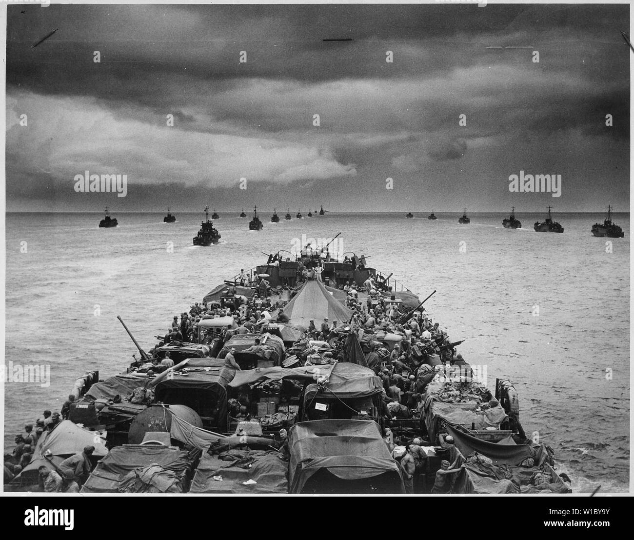 Columns of troop-packed LCIs trail in the wake of a Coast Guard-manned ...