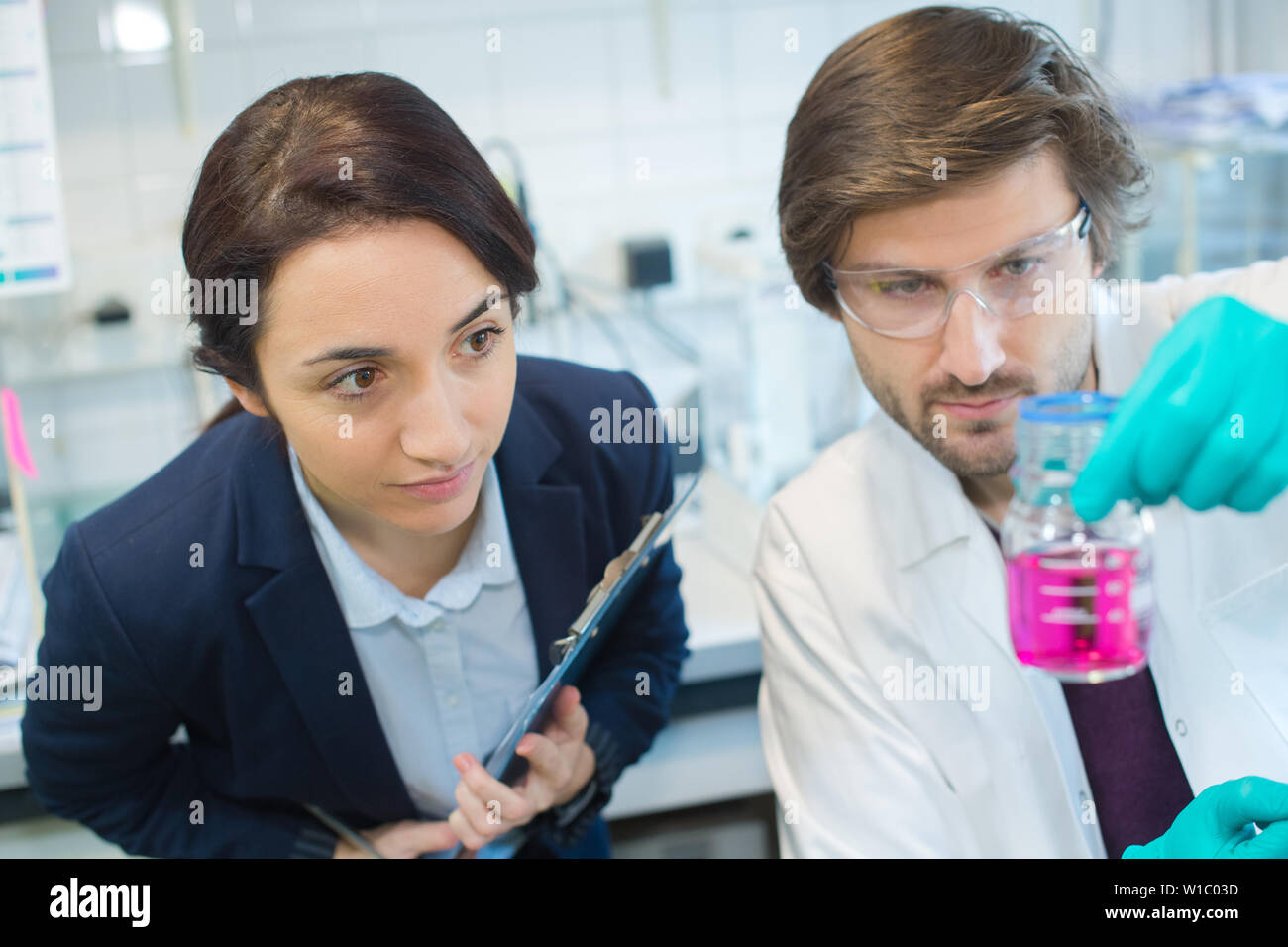 scientists looking at pink liquid in glass flask Stock Photo - Alamy