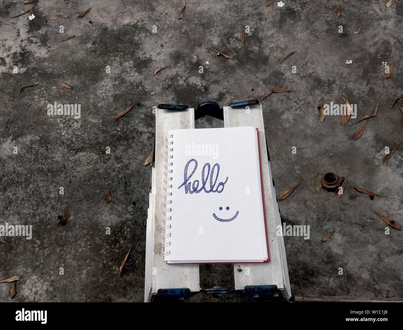 Hello text on notebook. Blank open notepad and black pen on staircase ...