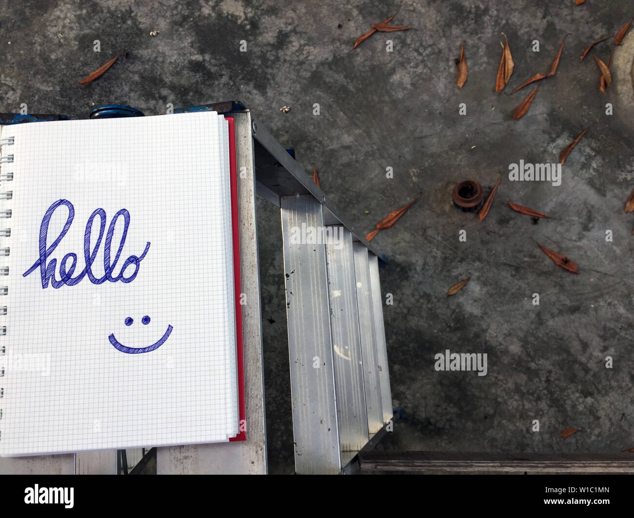 Hello text on notebook. Blank open notepad and black pen on staircase ...