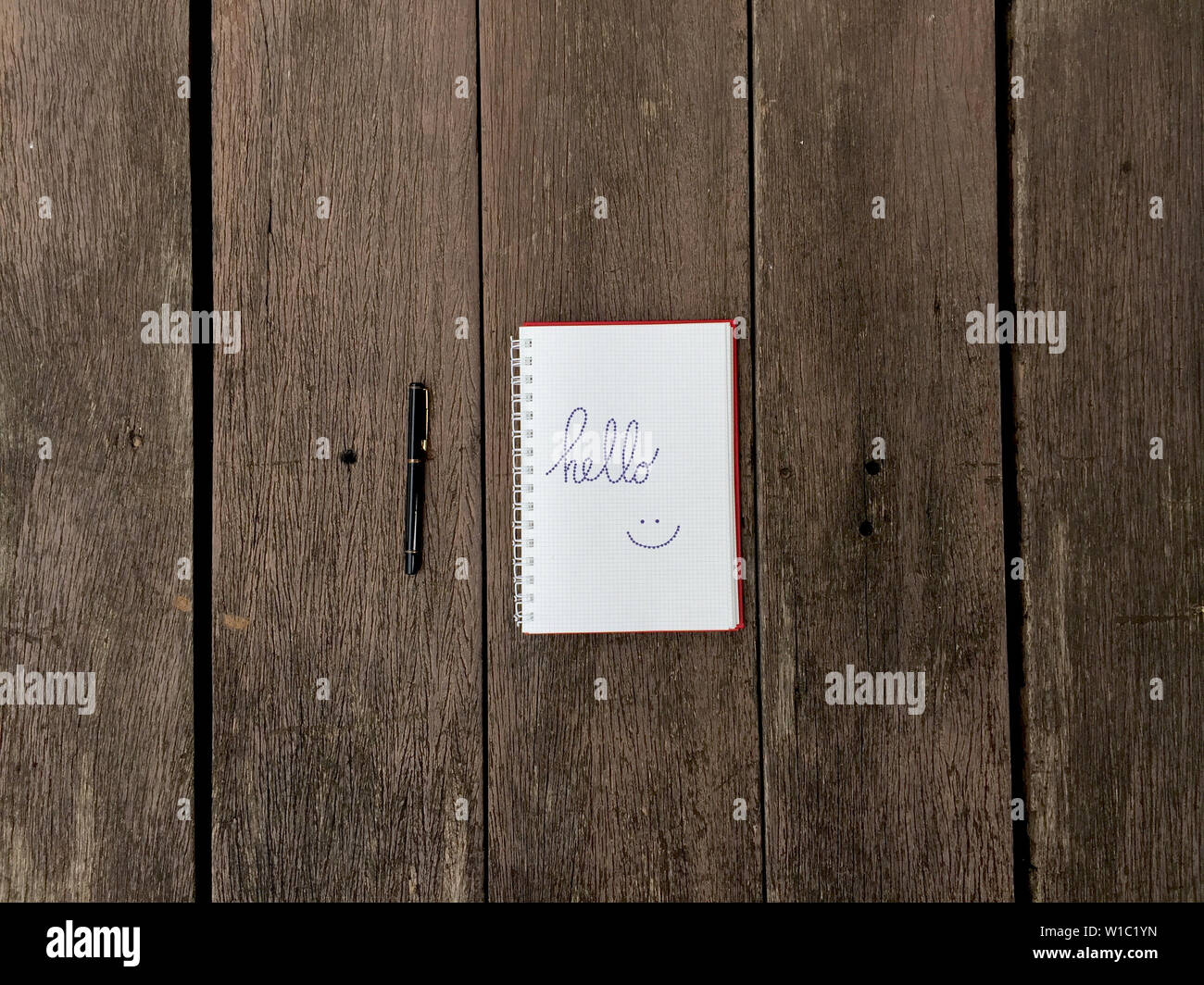 Hello text on notebook. Blank open notepad and black pen on old wood ...