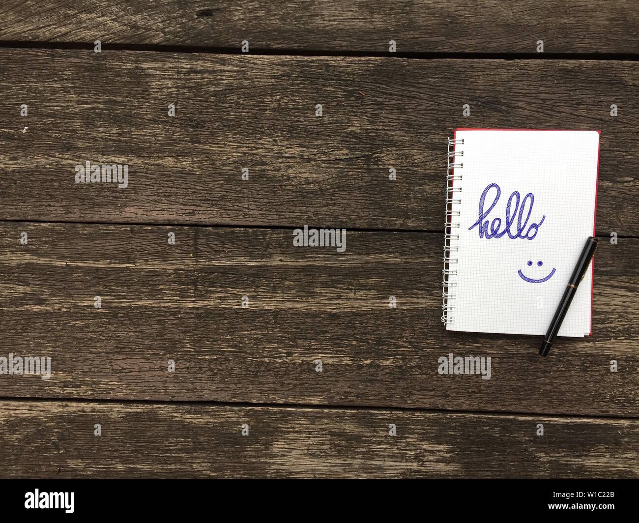 Hello text on notebook. Blank open notepad and black pen on old wood ...