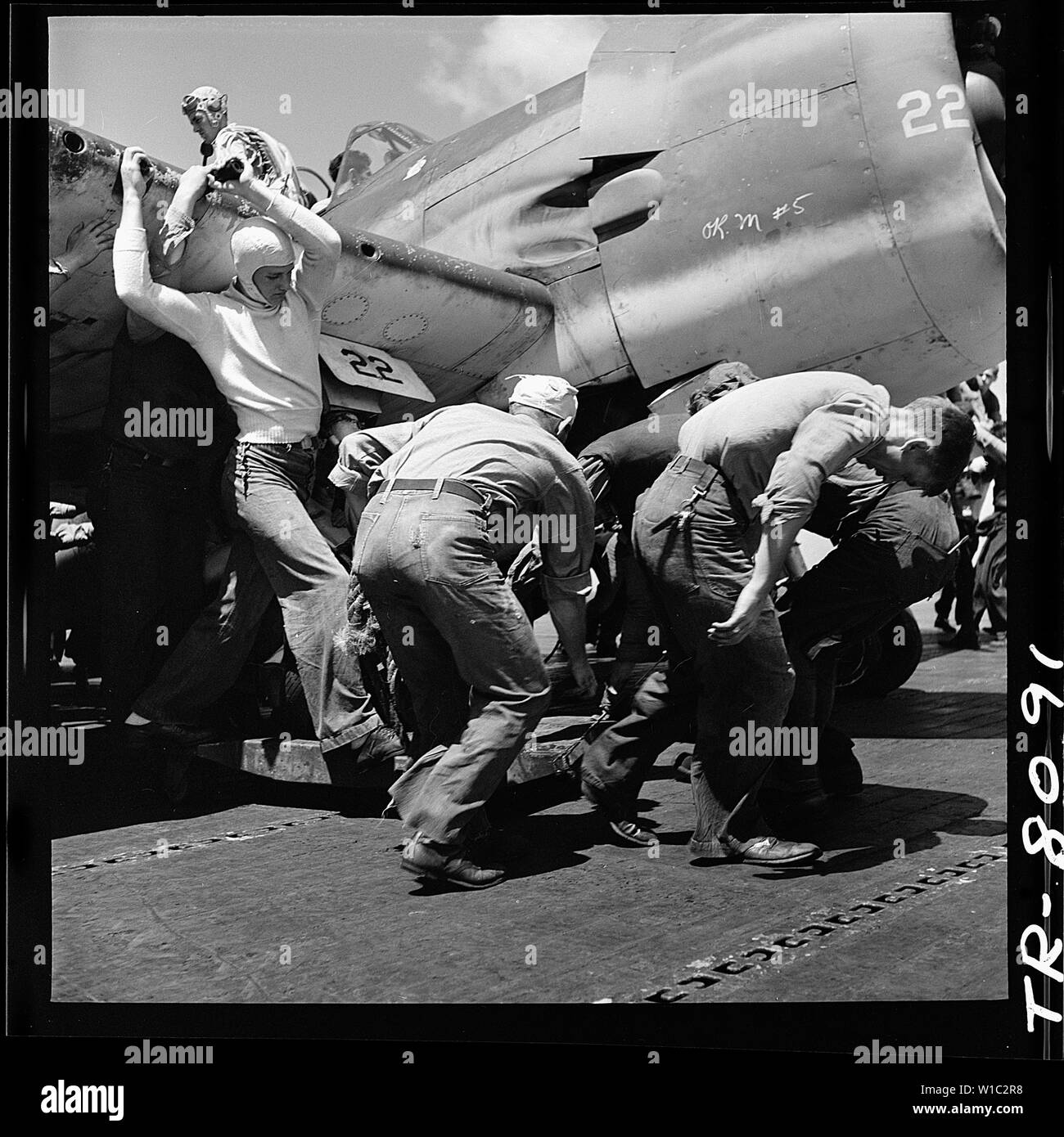 Crewmen hastily drag plane with flat tire down flight deck of USS ...