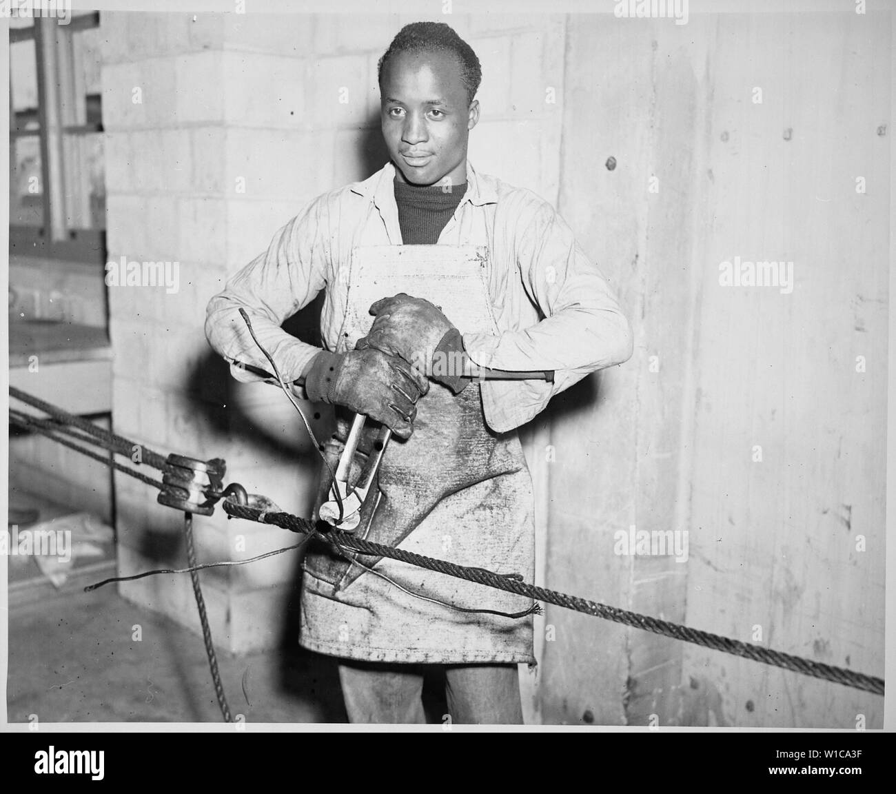 E. Perry, Seaman 1/c, is splicing steel cable... This is a highly ...