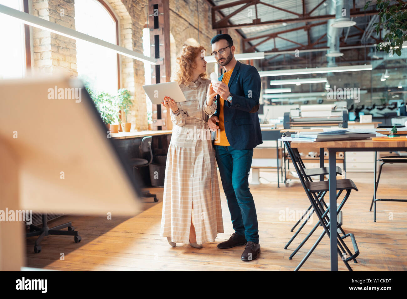 Talking to colleague. Curly red-haired interior designer wearing long ...