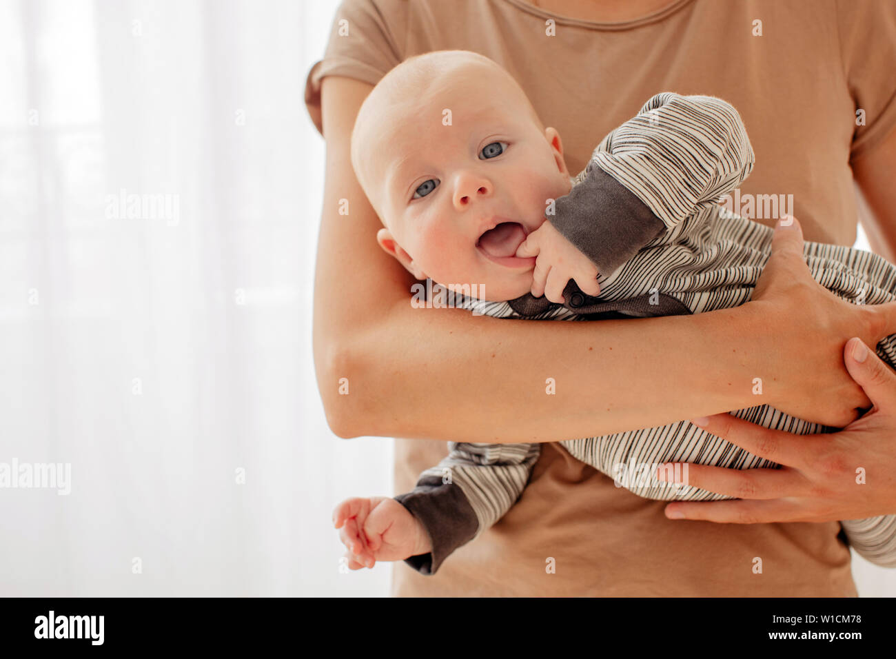 Curious cheeky baby on hands of mother Stock Photo - Alamy