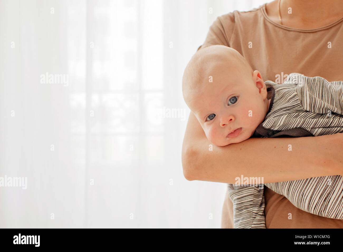 Curious cheeky baby on hands of mother Stock Photo - Alamy