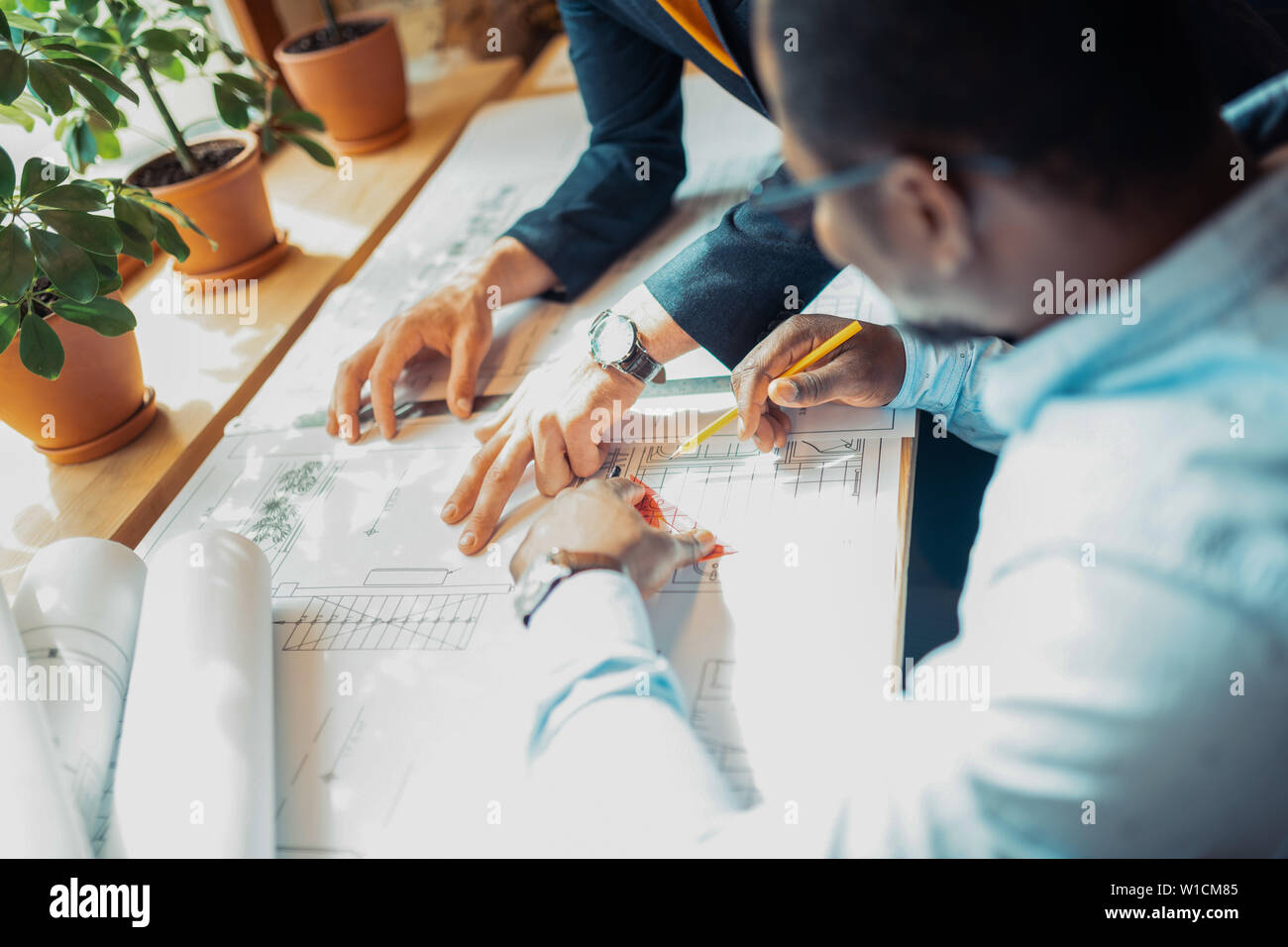 Holding pencils. Close up of men wearing watch holding pencils while ...
