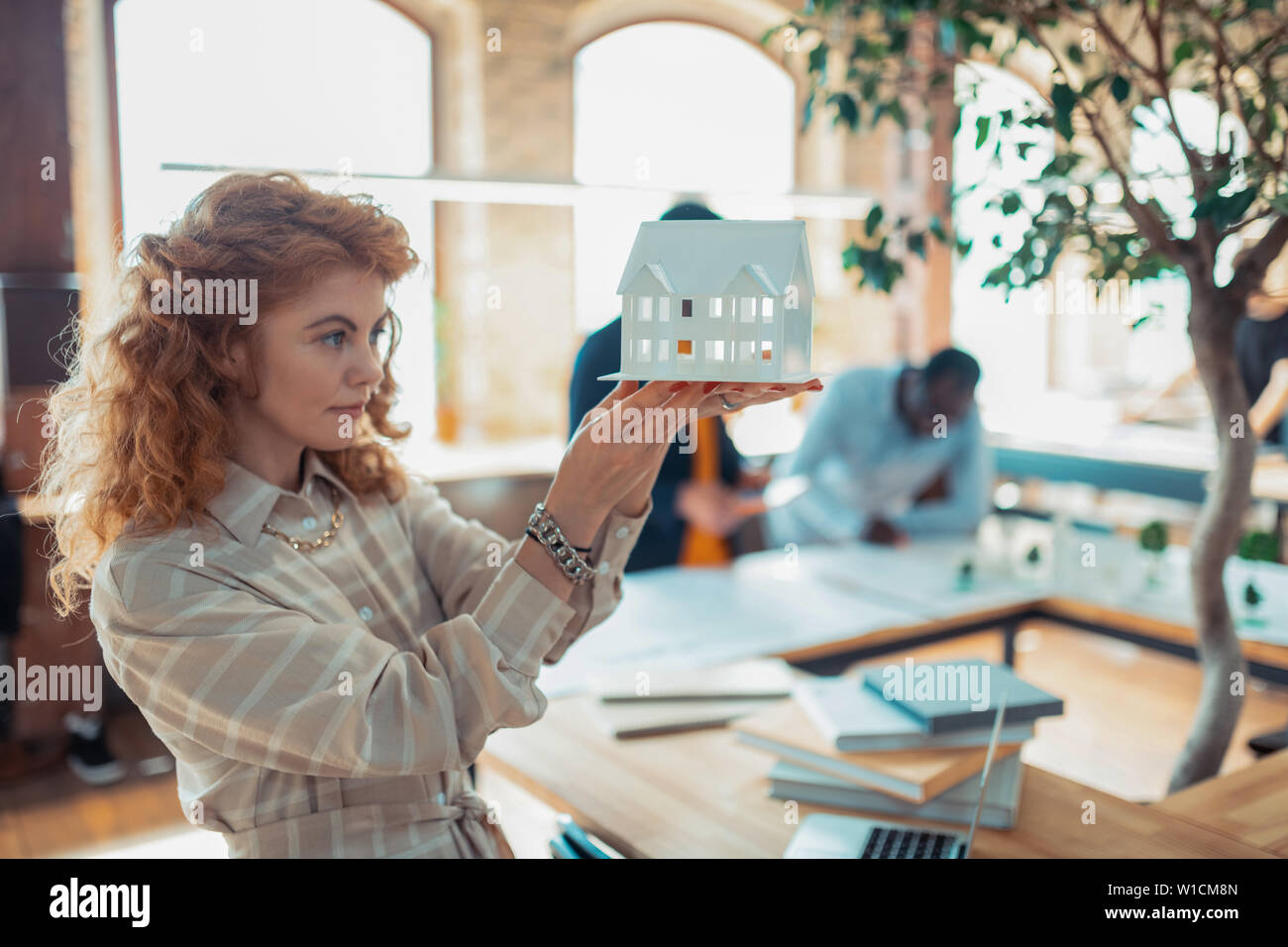 Holding little house. Curly red-haired interior designer holding little ...