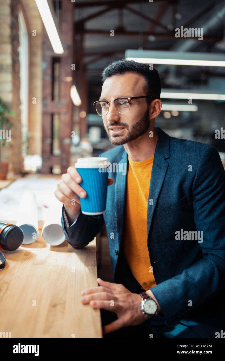 Coffee before work. Dark-haired handsome interior designer drinking ...