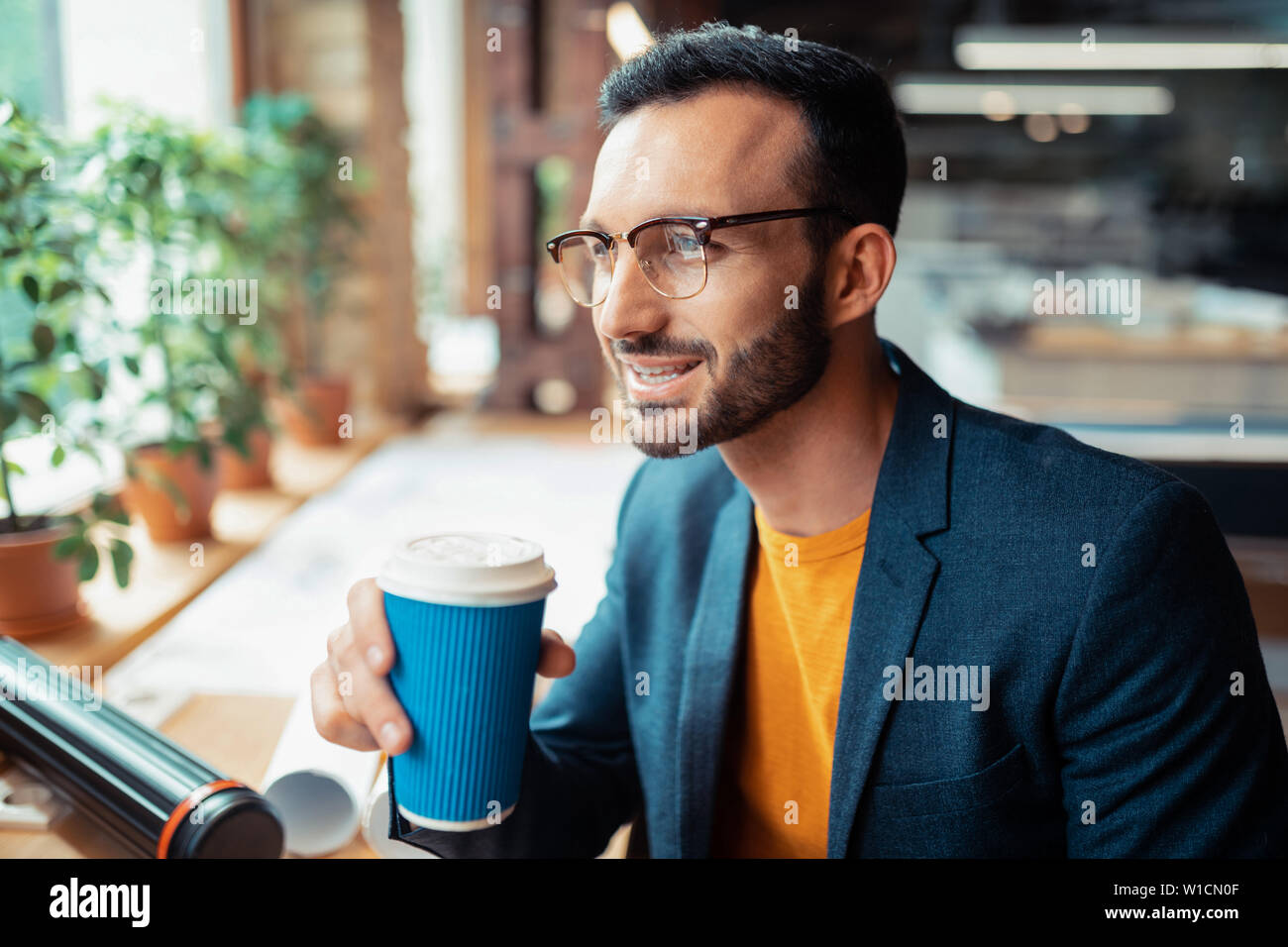 Coffee at work. Handsome man wearing dark jacket drinking coffee at ...