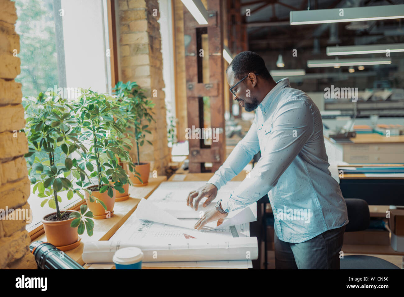 Ruler and sketches. Professional bearded dark-skinned designer using ...