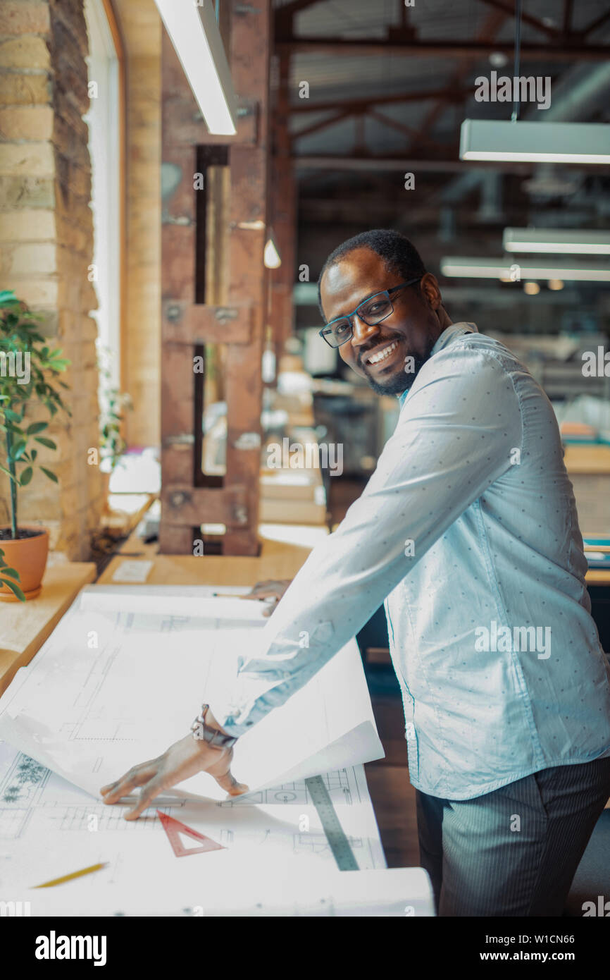 Designer smiling. Dark-skinned interior designer smiling while working ...